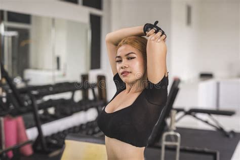 A And Sultry Asian Woman In A Black Crop Top Looking At Camera While Doing Tricep Stretches