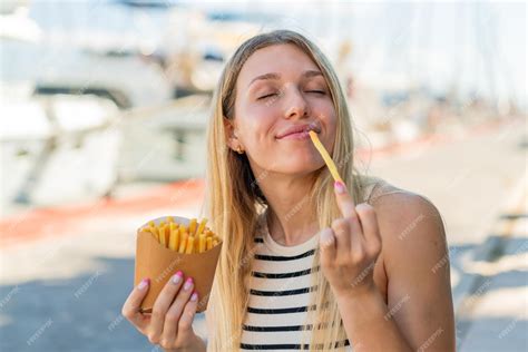 Premium Photo Young Blonde Woman At Outdoors Taking Fried Chips And Thinking