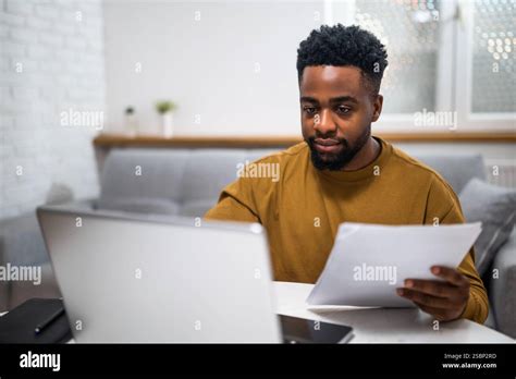 Successful African American Businessman Using Laptop And Analyzing Documents While Working