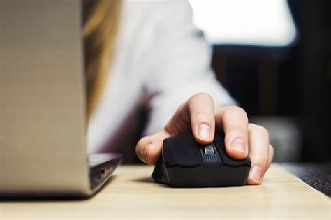 Premium Photo Computer Mouse In A Female Hand Laptop On A Wooden Table Working Environment Scene