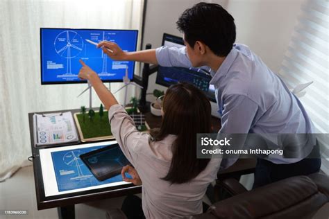 프로젝트 엔지니어 사무실에서 지속 가능한 풍력 터빈 및 태양 전지 에너지의 건축 계획이 포함된 데이터 화면을 보고 있는 동료들