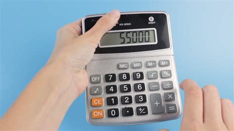 A Female Hand Is Doing Some Calculations On A Calculator Close Up On A Blue Background Stock