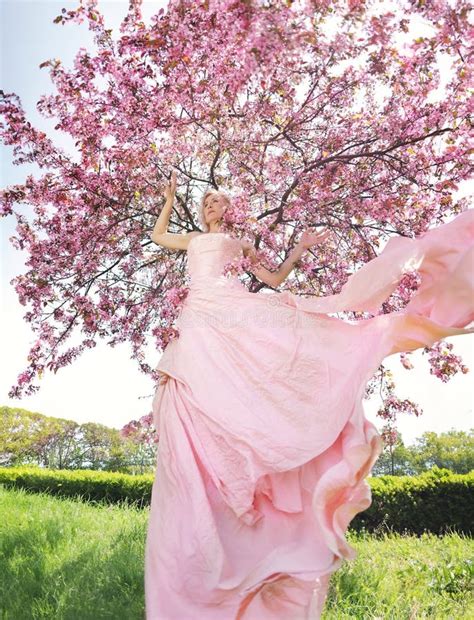 Majestic Mature Woman In Flowing Pink Gown Among Spring Blossoms