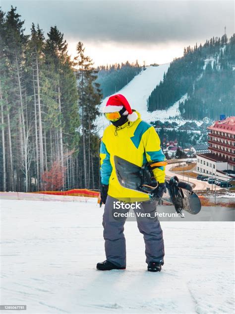 눈 덮인 언덕을 따라 걷는 빨간 크리스마스 모자를 쓴 스노우 보드를 입은 남자 걷기에 대한 스톡 사진 및 기타 이미지 걷기 겨울 관광 Istock