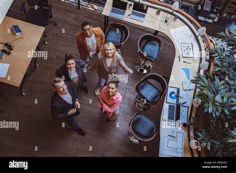 Group Of Coworkers Standing At Office And Looking Up At Camera
