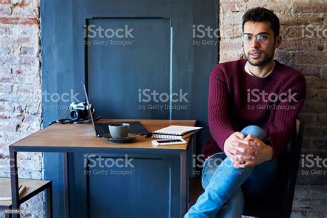 노트북 컴퓨터와 빈티지 카메라와 함께 테이블에 세련 된 커피숍에 앉아 광 안경에 남성 기자의 전체 길이 초상화 Hipster 남자 시간을 재현 하는 동안 카메라를 보고