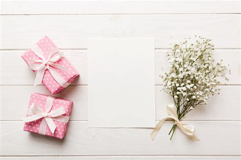 하얀 종이 목록과 꽃이 있는 결혼식 모형은 컬러 테이블 위에 평평하게 놓여 있다 빈 인사말 카드와 봉투 아름 다운 꽃 무늬입니다