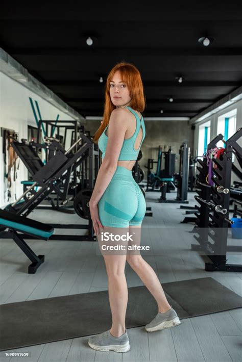아름 다운 빨간 머리 운동 여자는 체육관 클럽에서 기계 피트니스 근처에 서 있습니다 건강한 생활방식에 대한 스톡 사진 및 기타