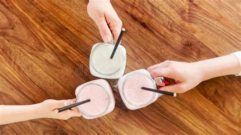 Three Girls Clink Glass Jars Filled With Milkshakes In A Cheerful Toast Friendly Celebration