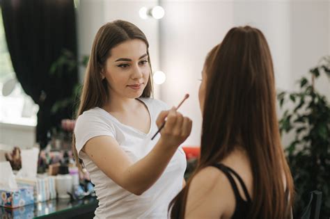 메이크업 아티스트는 뷰티 스튜디오에서 모델과 함께 작업합니다 우아한 빨간 머리 모델에 대한 패션 확인 립스틱에 대한 스톡 사진