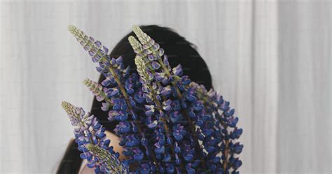 파스텔 직물의 배경에 루팡 꽃다발을 들고 린넨 드레스를 입은 세련된 여성 단순한 느린 생활 보헤미안 소박한 드레스를 입은