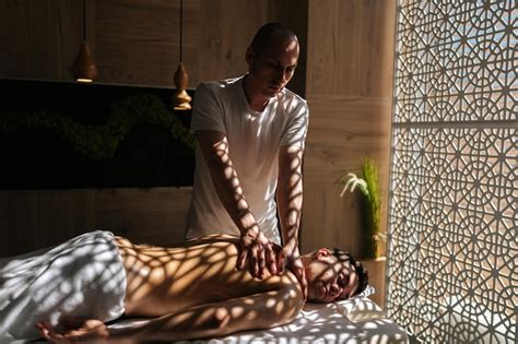 Vista lateral de um homem feliz recebendo massagem profissional nas costas de um massagista ...