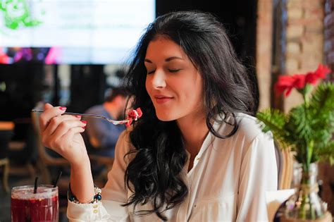 레스토랑에서 케이크의 큰 조각을 먹는 여자 점심에 사무실 노동자 카페에서 데이트하는 젊은 여성 케이크 접시를보고 어두운 곱슬 머리를 가진 매력적인 소녀 귀여운에 대한 스톡