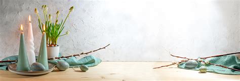 밝은 회 반죽 벽에 나무 테이블에 푸른 녹색 계란 청록색 냅킨 양초 및 화분에 심은 흰 포도 히아신스가있는 파노라마 형식의