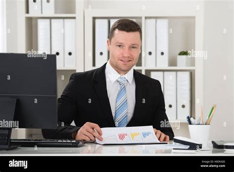 Happy Businessman Analyzing Financial Charts At Desk In Office Stock