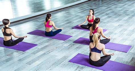 젊은 미소 로터스 위치에서 강사와 함께 요가 수업을 연습 하는 스포티 한 매력적인 여성 그룹 2015년에 대한 스톡 사진 및