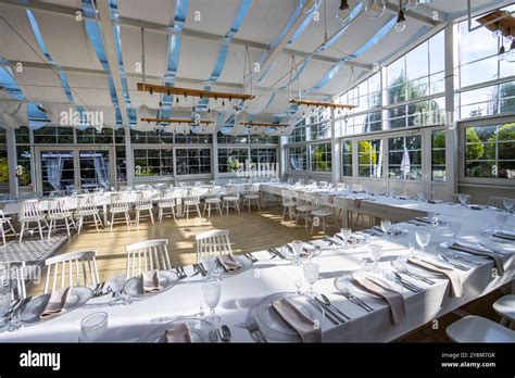 A Bright Glass Walled Banquet Hall With Tables Covered With White