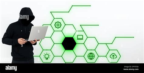 Male Programmer In Black Hoodie Stands And Holds Laptop Hacker With Hood On His Head Typing