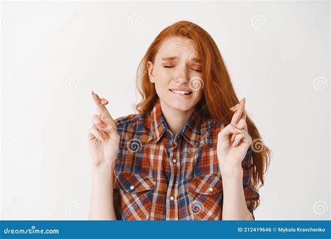 Worried Redhead Girl Making A Wish With Crossed Fingers And Closed Eyes
