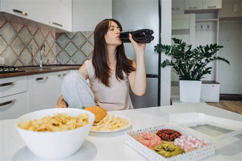 A Woman Eats Junk Food At Home In The Kitchen Stock Photo By Dmytros