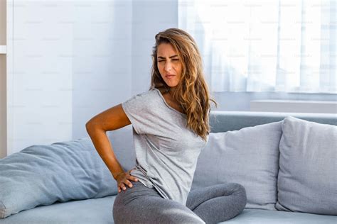 집에서 요통으로 고통받는 여자 허리 통증 여자는 아픈 근육을 마사지하는 허리 통증을 느끼고 슬픈 여자는 허리로 고통받습니다 사진 Unsplash의 요통 이미지