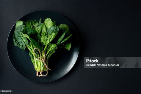 깨끗한 음식 개념 검은 배경에 접시에 신선한 유기농 시금치 채소의 잎의 무리 건강한 해독 봄 여름 다이어트 비건 생 식품 공간을 복사합니다 건강관리와 의술에 대한 스톡 사진
