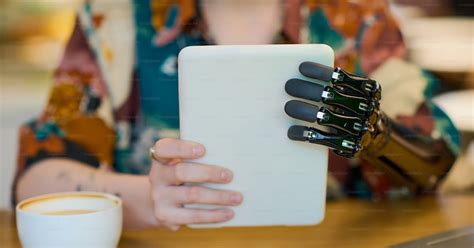 근전기 팔을 가진 젊은 여성의 손이 카페의 테이블 옆에 앉아 커피를 마시는 동안 태블릿을 들고 있다 사진 Unsplash의 러시아 이미지