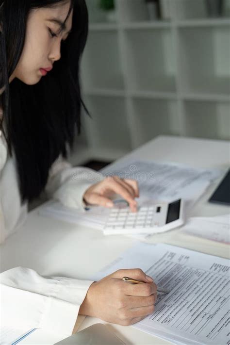 Close Up Of A Young Woman Calculating Taxes And Filling Out Financial