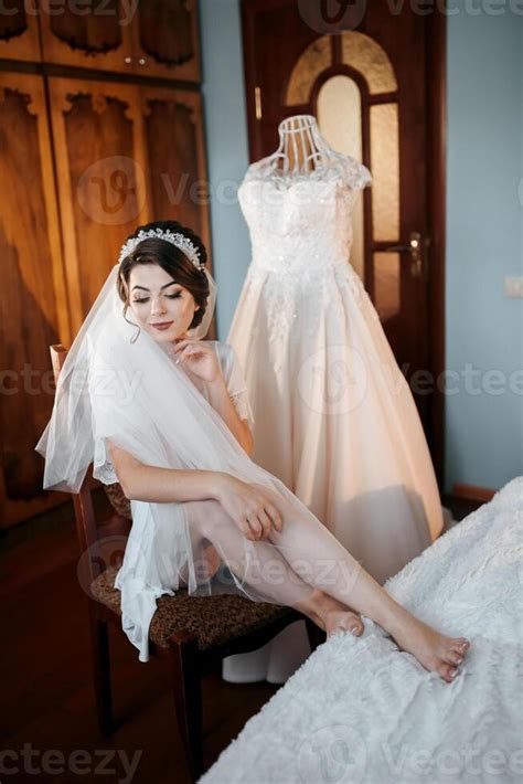A Bride Is Sitting On A Chair In Front Of A Wedding Dress 53432546