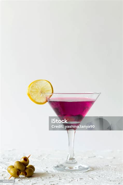 바에서 국제적인 칵테일을 즐기며 즐기신다 흰색 배경에 올리브와 레몬 붉은 칵테일의 마티니 유리 테이블에 마티니 안경 복사 공간을 복사합니다 알코올 음료 수직 0명에 대한