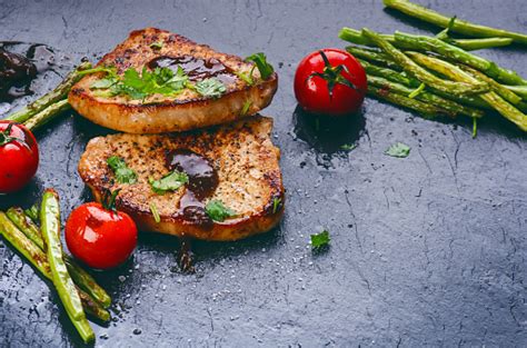 구운된 돼지고기 볶음 야채 토마토 콩 블랙 슬레이트에 소스와 스테이크 거품과 신선한 고기입니다 어두운 배경입니다 구이 및 바베 큐 개념 가금류에 대한 스톡 사진 및 기타