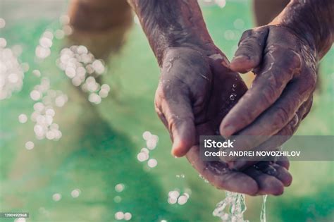 남자는 손에서 손으로 아쿠아 방울을 통과하고 열린 손바닥에 액체를 꺼내십시오 사진을 클로즈업합니다 남성의 강한 팔에 진정한 자연의 아름다움 맑은 바다 순수한 물 절약 환경