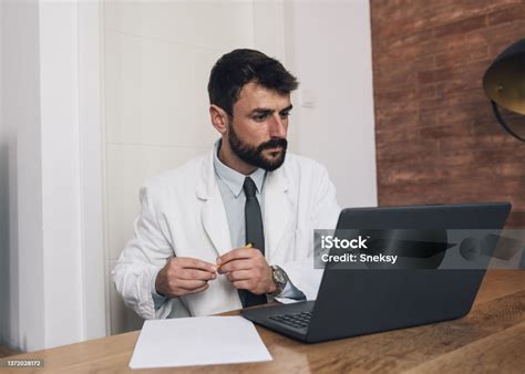의사는 주의 깊게 자신의 컴퓨터에 있는 일부 파일을 읽습니다 남성에 대한 스톡 사진 및 기타 이미지 남성 의사 읽기 Istock