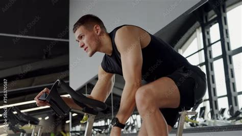 A Man Is Pedaling On An Exercise Bike At The Gym Working Out His Thigh Muscles And
