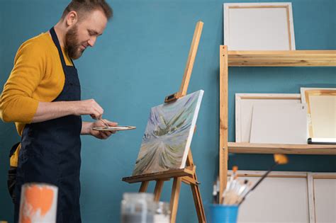 남자 화가는 캔버스 앞에 서서 그림을 그렸다 유성 페인트 아티스트 브러시 캔버스 및 프레임을 사용하는 아티스트 워크샵 또는 미술 수업 창조적 인 개념 작품집에 대한 스톡