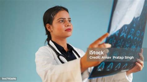 환자의 Ct 스캔 엑스레이 컴퓨터 단층 촬영 앞치마를 입은 쾌활한 아시아 인도 여성 의사 파란색 스튜디오 배경 위에 격리된 청진기를 검사하는 젊은 여성 의사의 초상화 단층