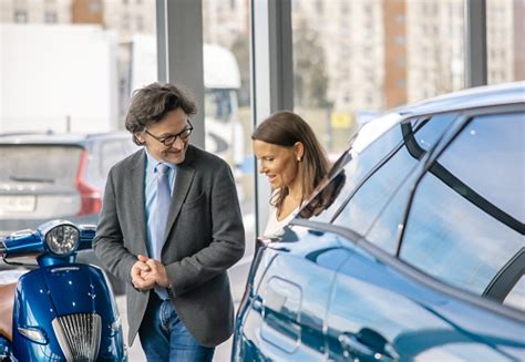 남성 자동차 딜러는 여성 고객과 이야기하고 서로 옆으로 걷고 자동차 딜러는 웃으며 손을 접고 Suv는 앞에 있습니다 2명에 대한