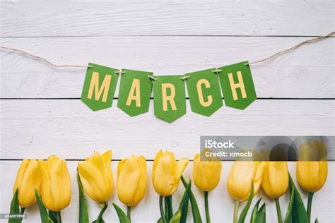 3 월 종이 갈 랜드 레터링 문자 편지 비문 흰색 나무 판자 소박한 반 시골 테이블 Backgropund에 노란 튤립 테두리 프레임 아름 다운 수평 평면 누워 봄 엽서 0
