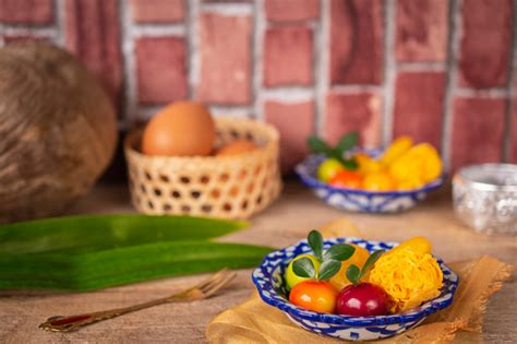 황금 천과 나무 테이블에 배치 흰색과 파란색 줄무늬의 접시에 태국 디저트 비슷한 개체 판단 물 그릇 바구니에 계란과 코코넛 옆에 배치 뒤편과 포크에 배치 0명에 대한 스톡