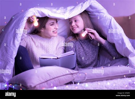 Happy Mom And Daughter Reading Under The Blanket With Torches Stock
