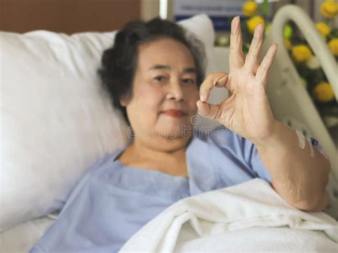 Asian Senior Female Patient Lying In Hospital Bed Smiling And Showing