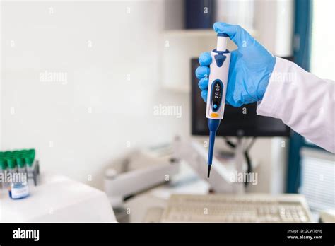 Laboratory Technician Holding Pipette Tool In His Hand In Blue Laboratory Technician Holding Pipette Tool In His Hand In Blue
