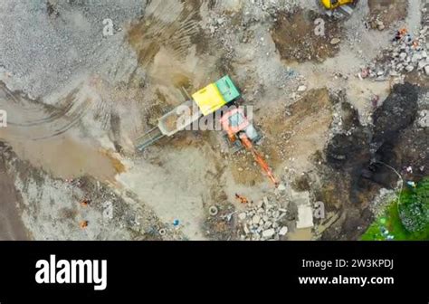 Working Excavators On The Site Of A Demolished Building Loading Cement Residues Into The