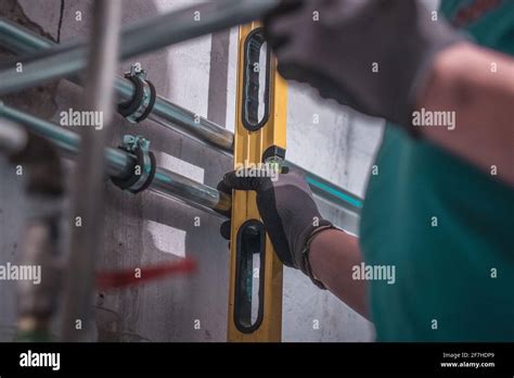 Person Using Water Level To Align Water Pipes For Plumbing While Renovating A House Pipework