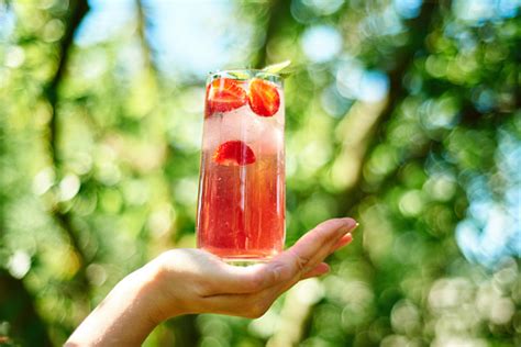 녹색 배경야외에서 유리에 얼음과 민트와 손에 신선한 딸기 레모네이드를 들고 여자 복사 공간 추운 여름 음료 베리 칵테일을 곁들인 스파클링 글래스 건강한 생활방식에 대한 스톡