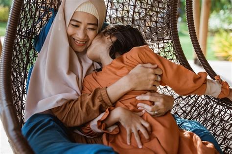 Premium Photo Muslim Mother And Daughter Sitting And Cuddling On A Chair Together
