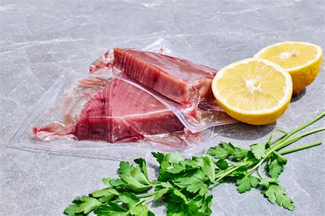 회색 대리석 배경에 진공 패키지에 붉은 참치 필렛 신선한 생선 레몬 파슬리요리 재료 건강한 식습관의 개념 단백질 0명에 대한