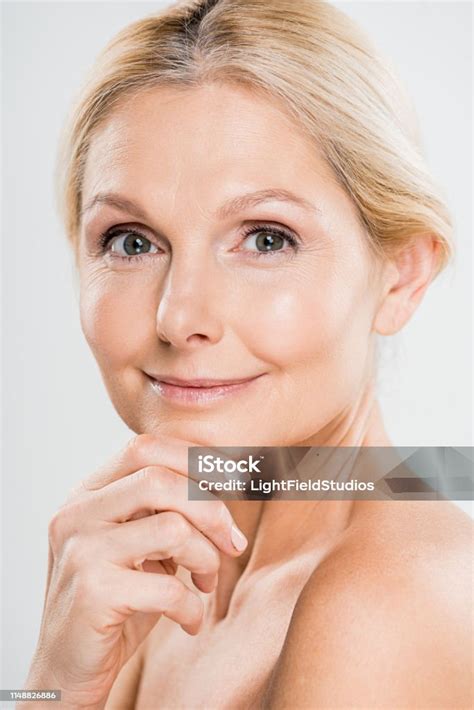아름 답 고 성숙한 여 자가 카메라를 보고 만지고 그녀의 얼굴에 회색 배경 금발 머리에 대한 스톡 사진 및 기타 이미지 금발 머리 만짐 미소 Istock