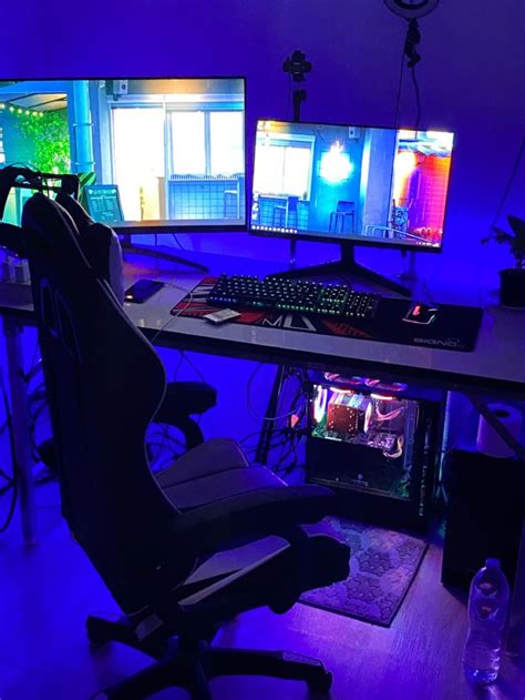 A Computer Desk With Two Monitors And A Gaming Chair In Front Of It On A Hard Wood Floor
