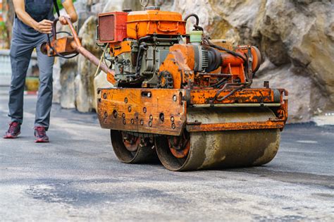 도로 작업 중 아스팔트 파버 기계 포장 작업을위한 건설 현장에서 도로 기계 도로 공사를위한 모래를 규준 개발에 대한 스톡 사진